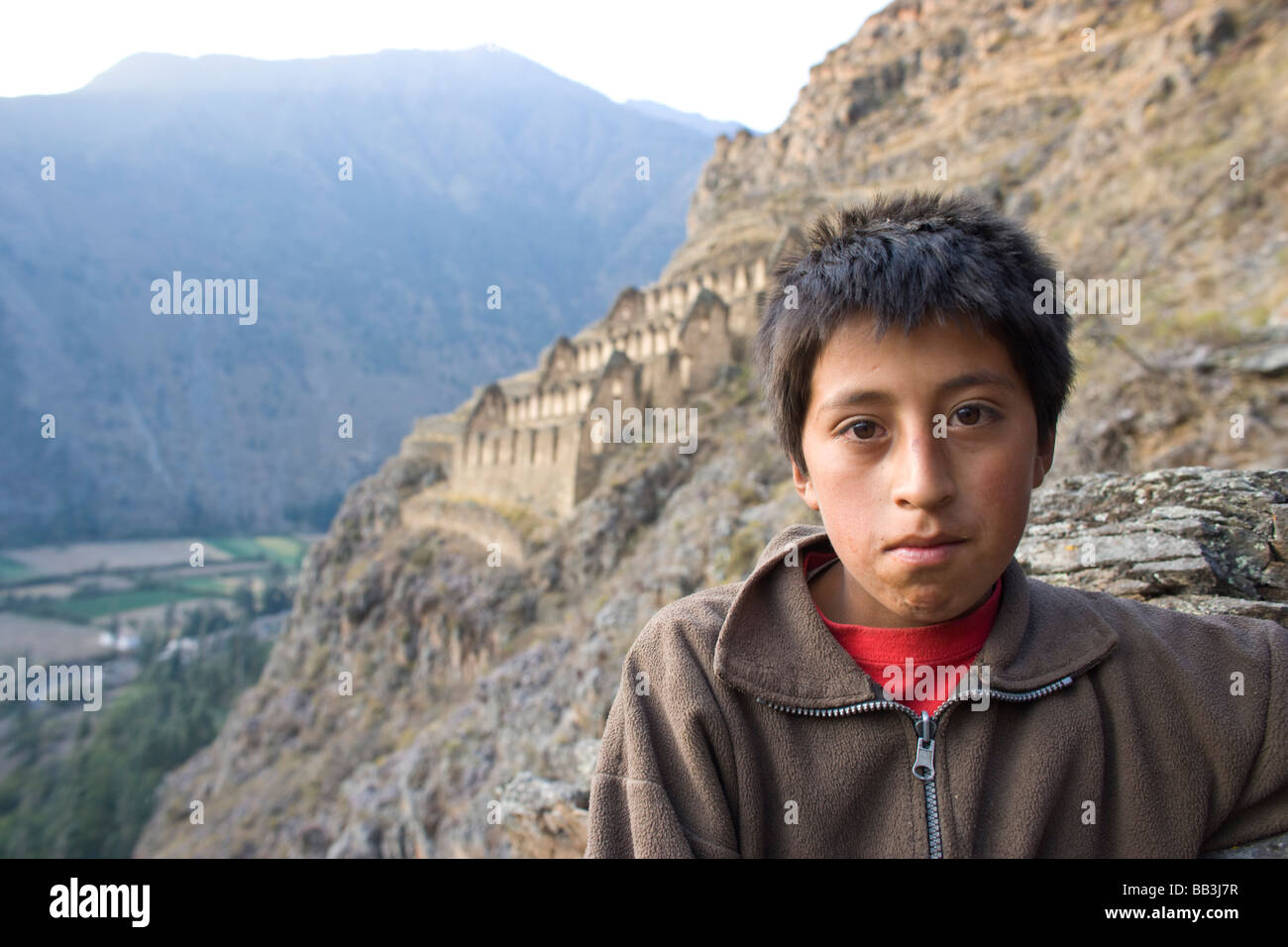 Boy in front of Aztec granary with town below, Ollantayambo, Peru Stock ...
