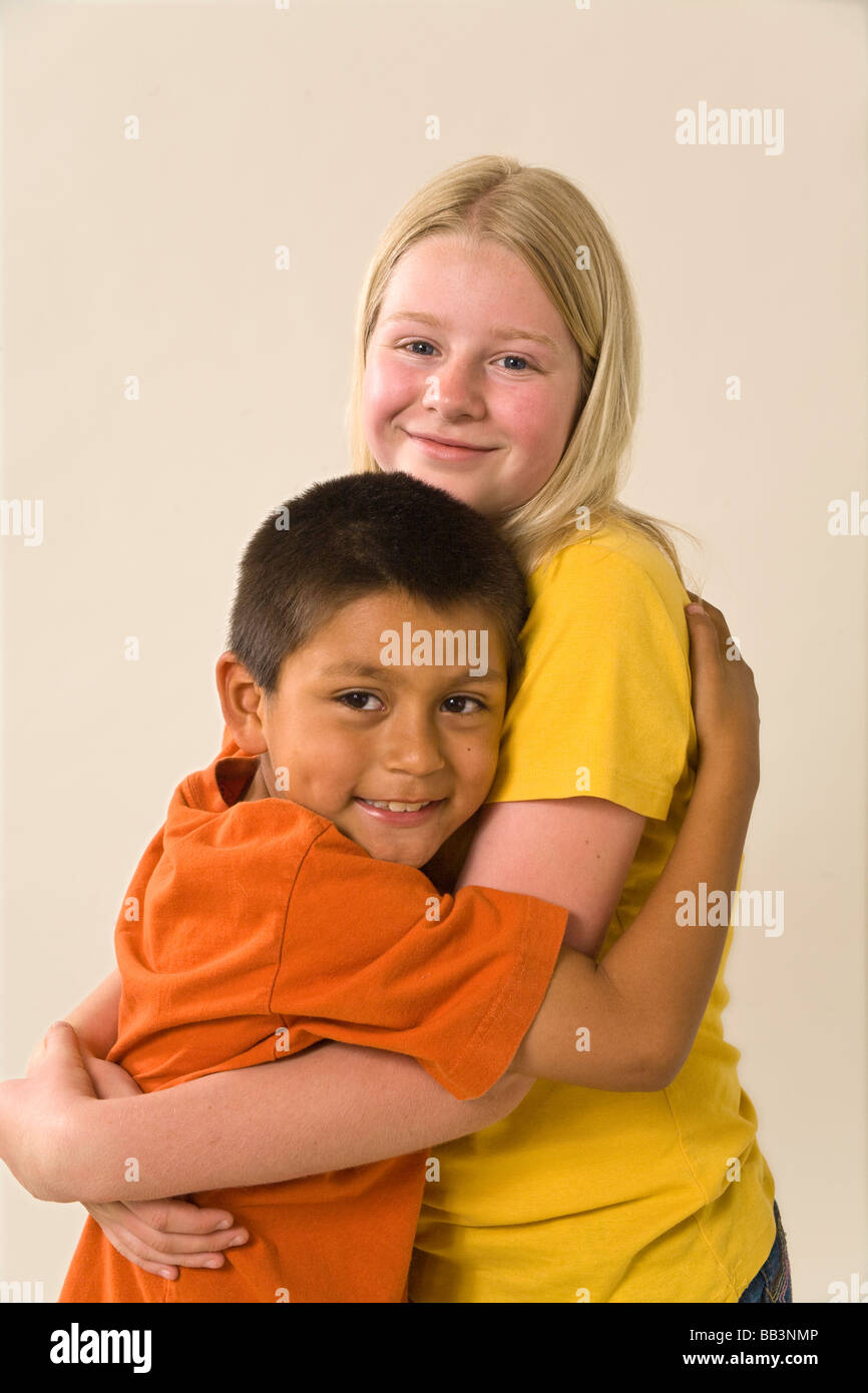 Adopted Hispanic boy hugs his new caucasian sister MR © Myrleen Pearson ...