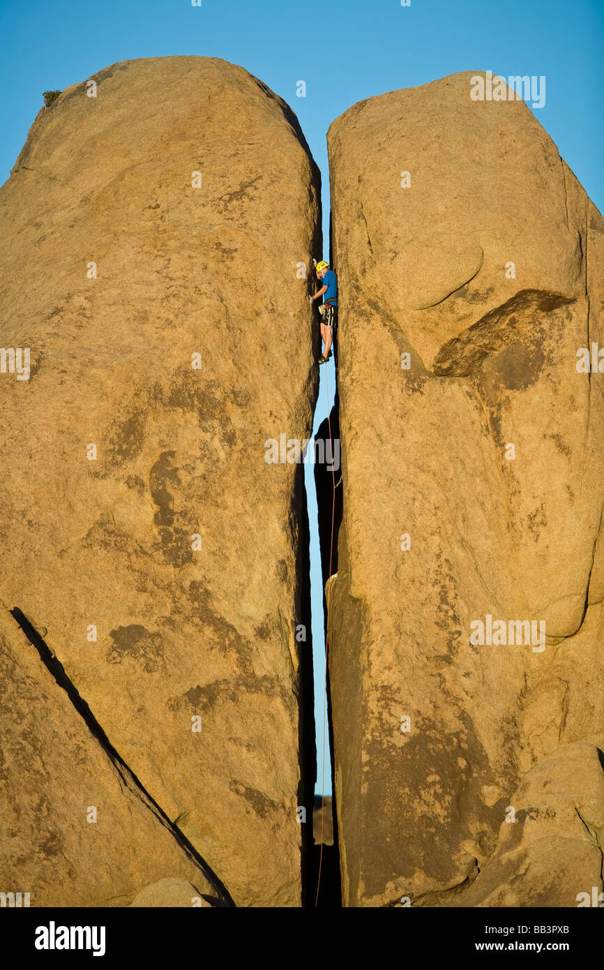 Climber squeezes his way up the gap in a split pillar in Joshua Tree ...