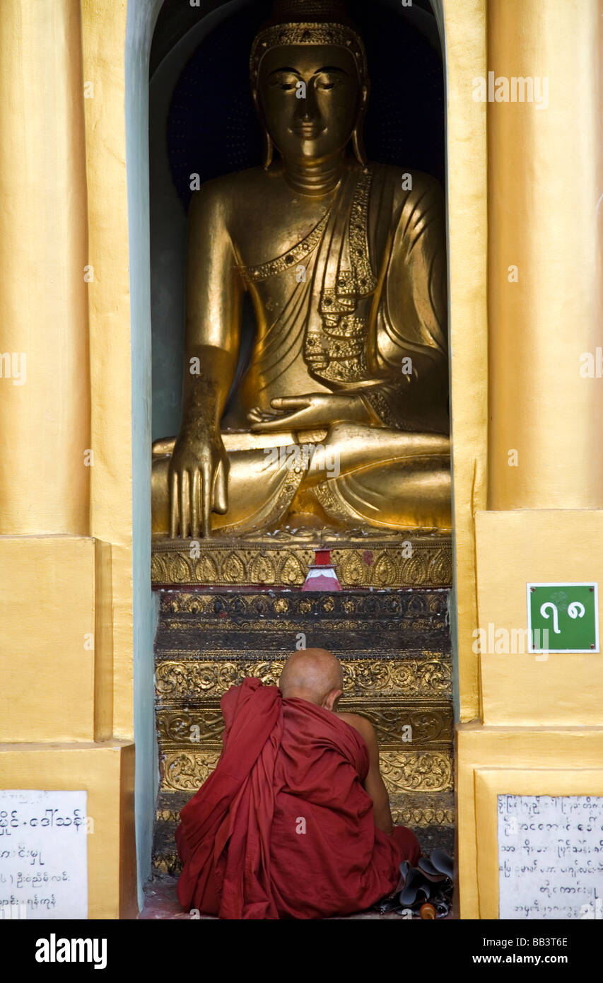 Buddhist monk praying in front of Buddha statue. Shwedagon Paya. Yangon ...
