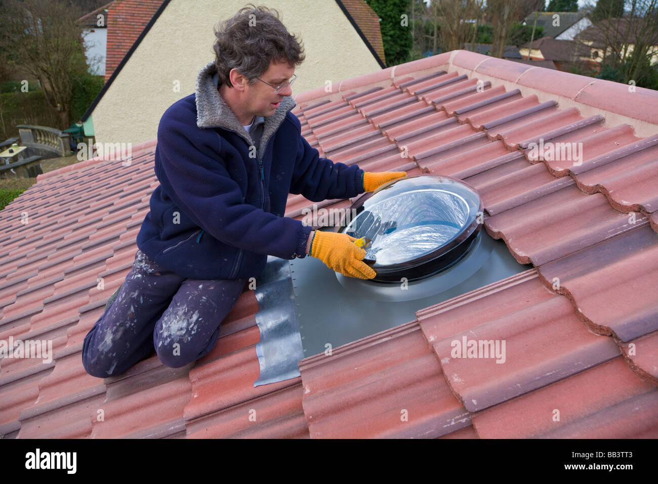 Man installing a sun pipe into a tiled roof Stock Photo - Alamy
