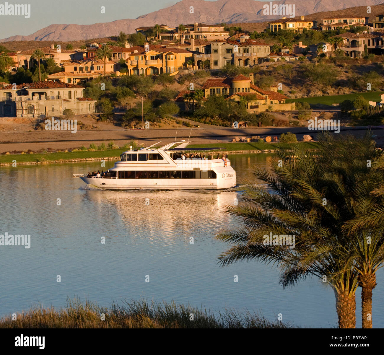 A white boat filled with passengers , tours Lake Las Vegas at dusk with ...