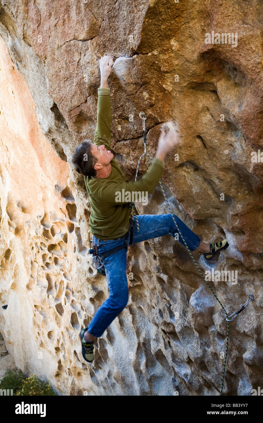 Climber clinging to rock face Stock Photo - Alamy