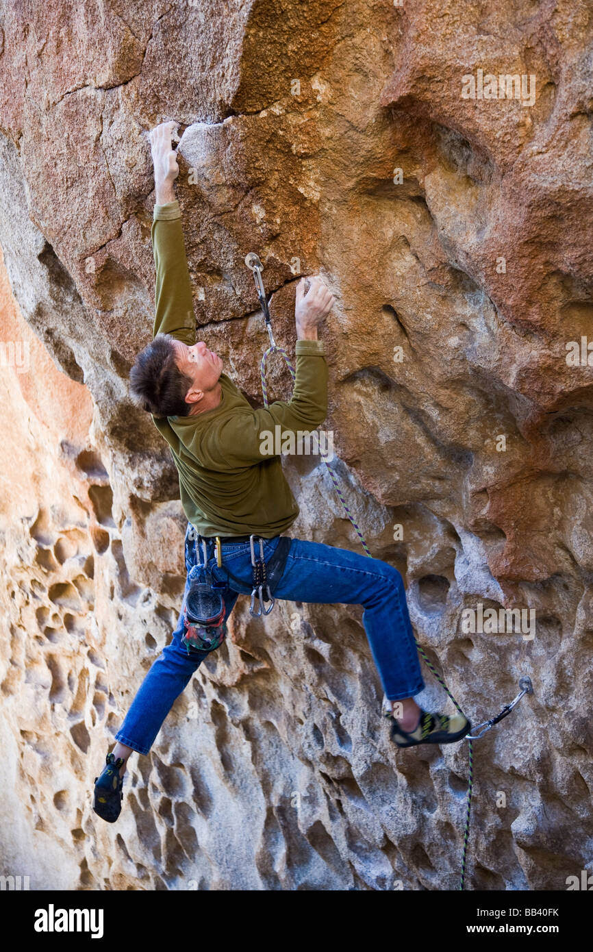 Climber clinging to rock face Stock Photo - Alamy