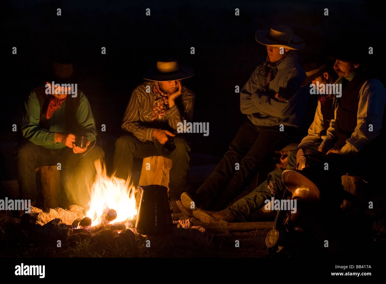 USA, Oregon, Seneca, Ponderosa Ranch. Cowboys sitting around a campfire ...