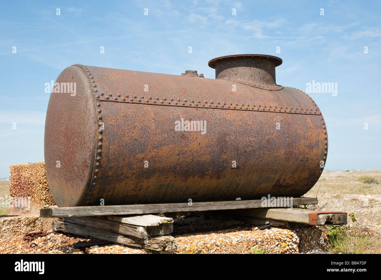Close up detail of old rusty fuel tank on wood planks against blue sky ...