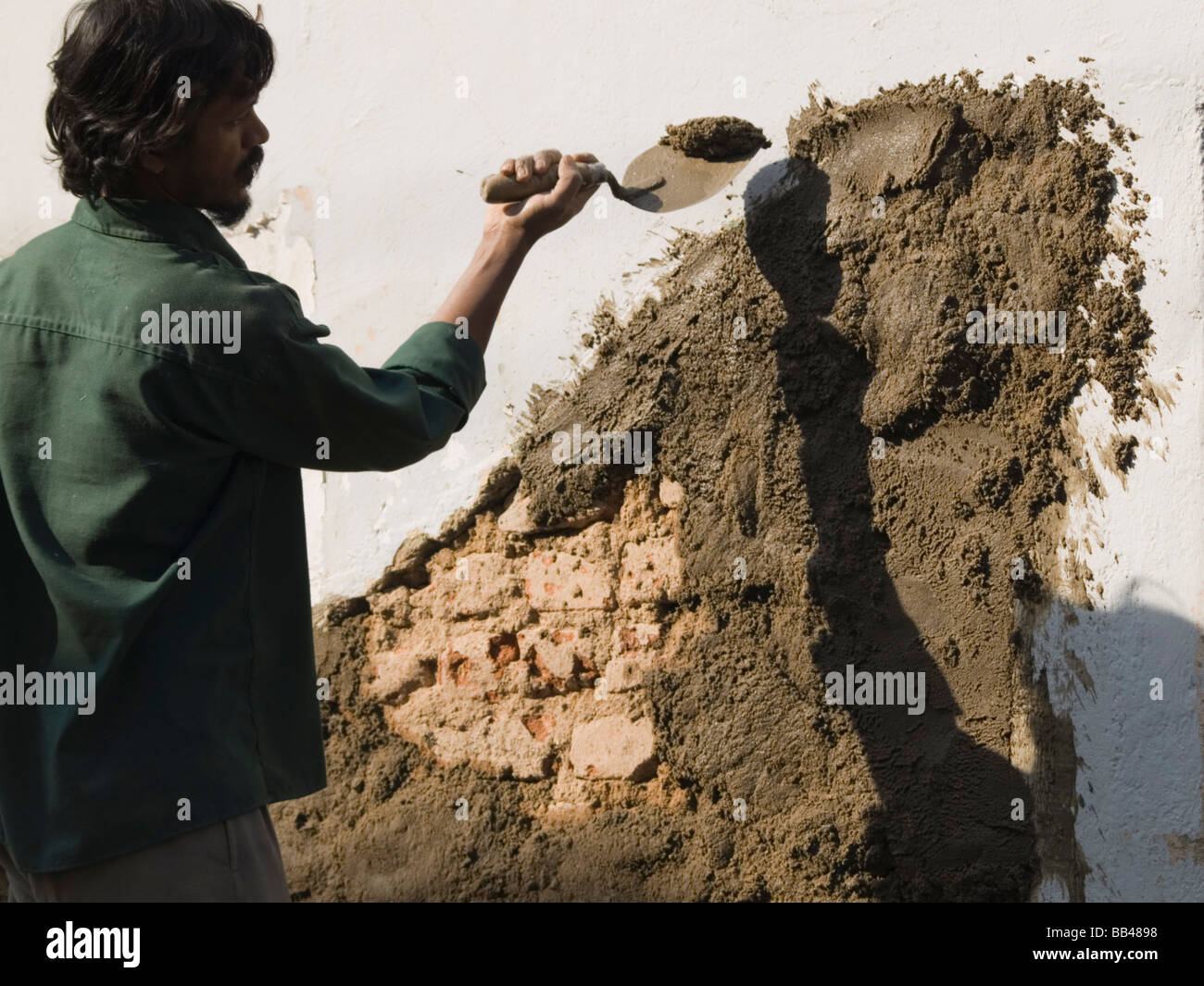 Man working on a construction site applies cement to a wall in ...