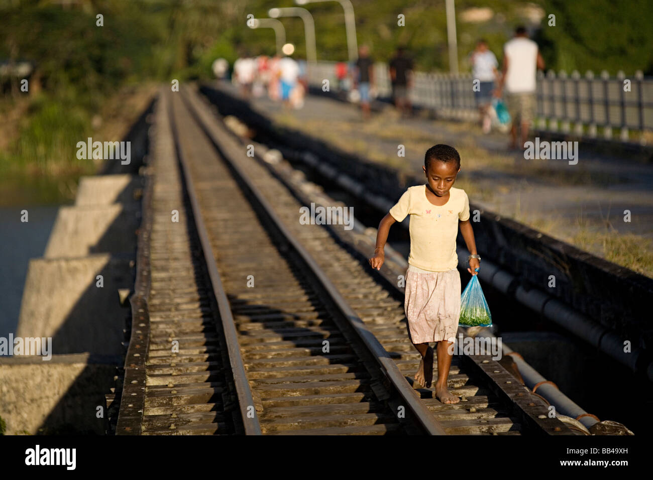 Young girl wearing a dress walks near train tracks while crossing a ...