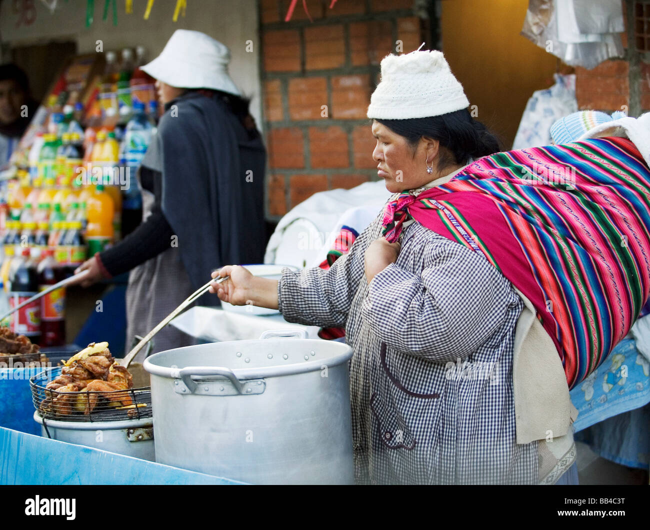 A street vendor in La Paz, Bolivia prepares some chicken while carrying ...