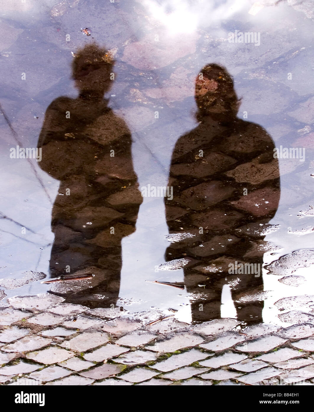 The shadows of two figures, reflected in a puddle Stock Photo - Alamy