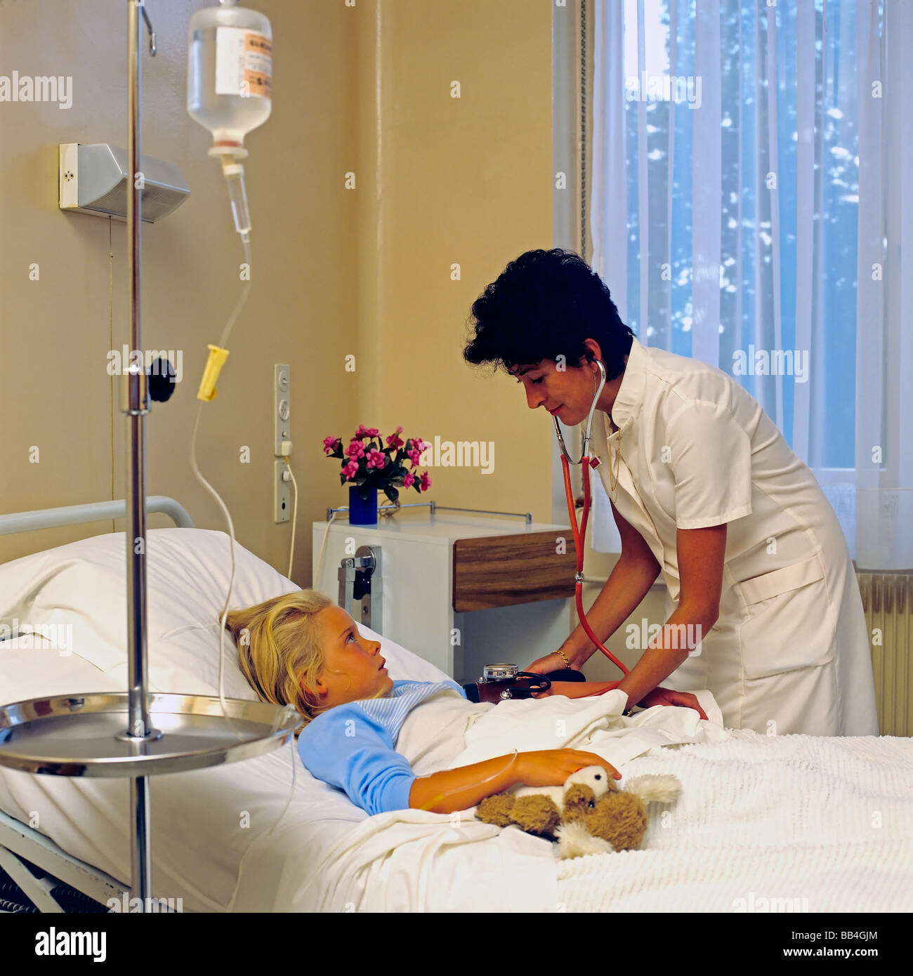 Nurse checking the pulse rate of a little girl child patient in ...