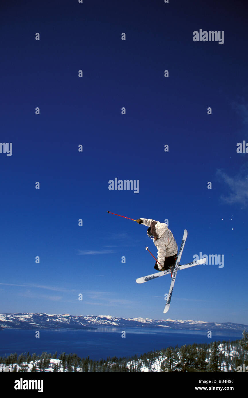 Skier spinning in the air and grabbing above a blue lake Stock Photo ...