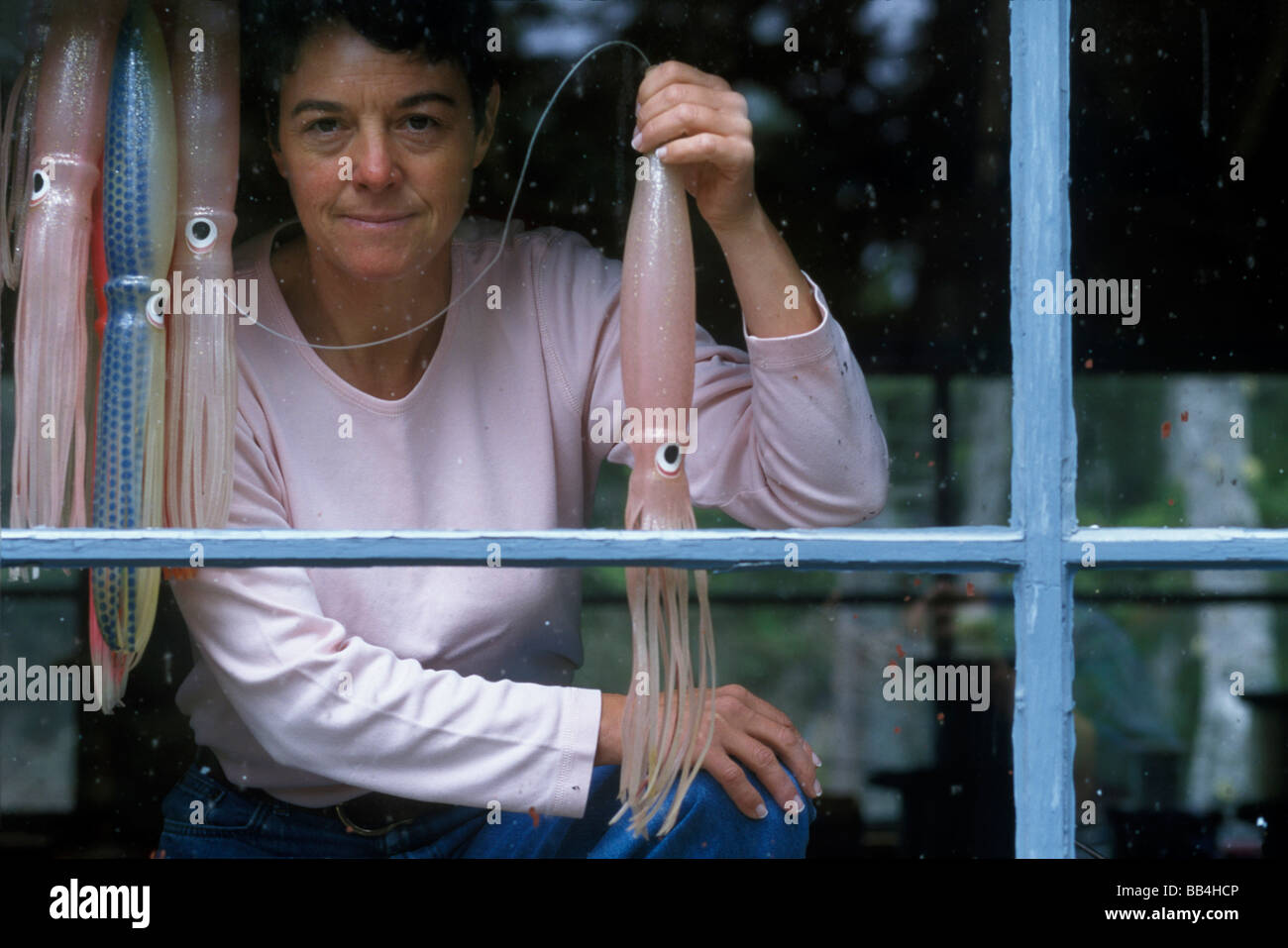 A woman holds a fake squid in her hand as she looks out of a window at ...