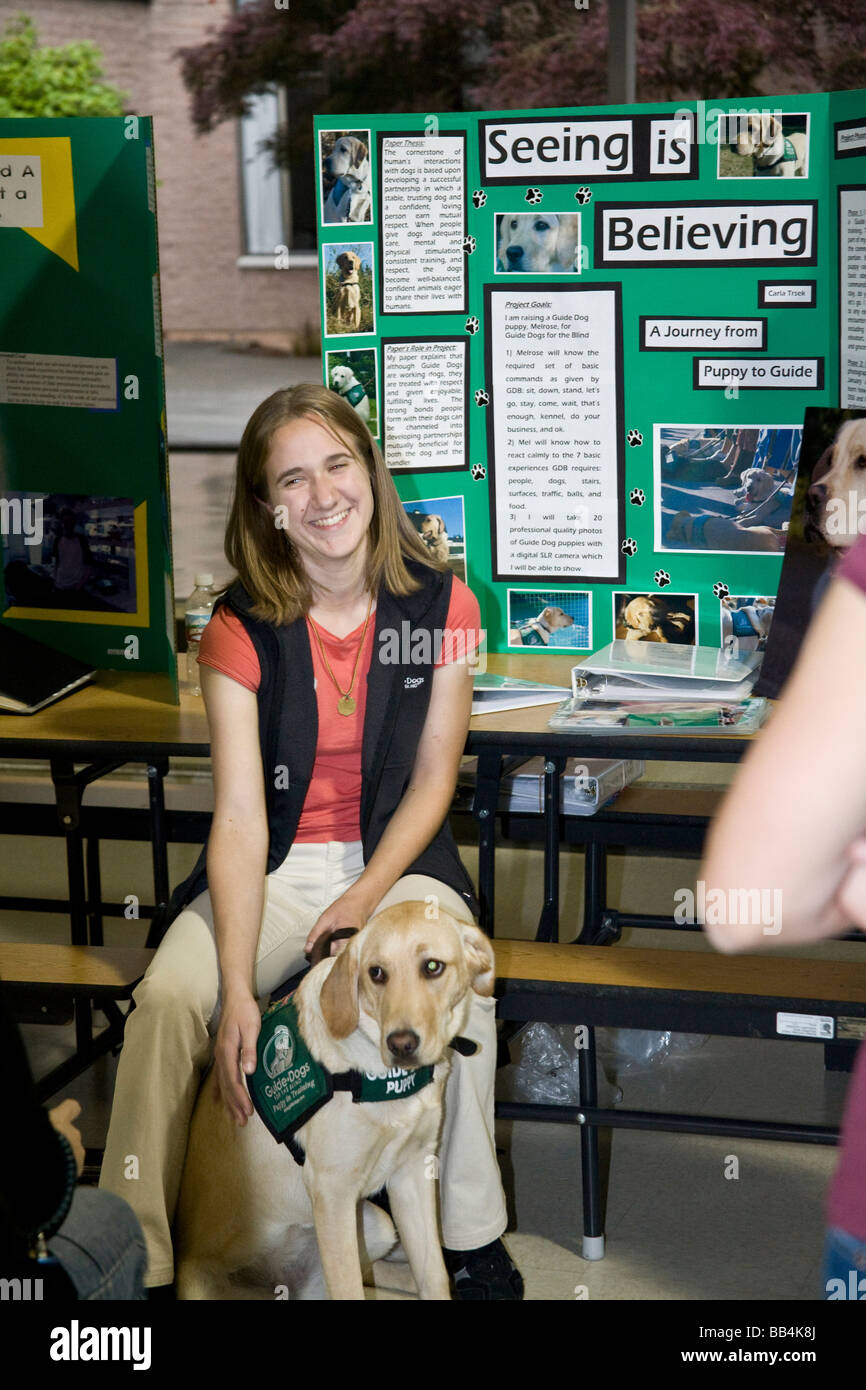 A high school student sits with a dog as she displays her high school ...