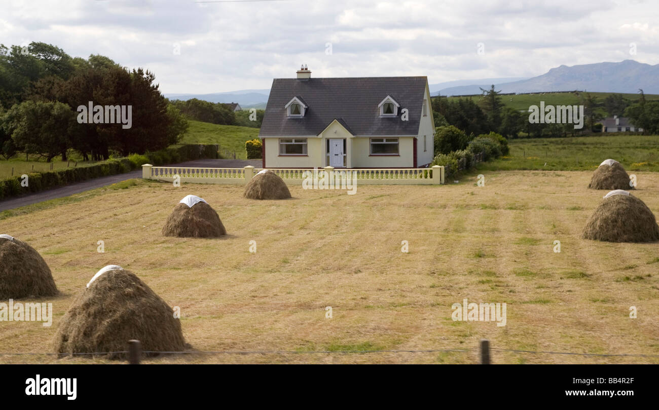 Ireland, County Mayo. Traditional haystacks dot the front yard of a ...