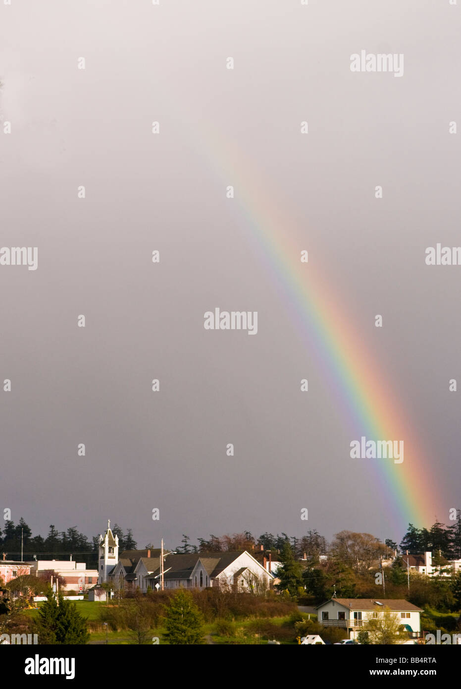 USA, WA, Whidbey Island. Brilliant rainbow after a storm rises from ...
