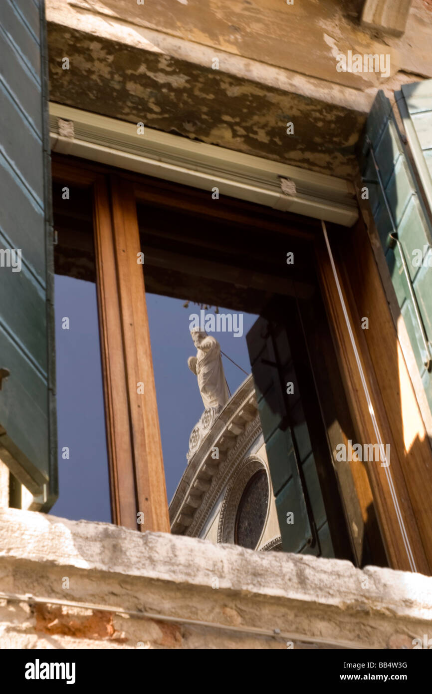 Europe, Italy, Venice. A reflection of a church statue in a window ...