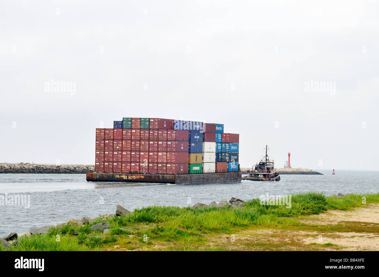 Tugboat pulling a container barge loaded with stacked shipping ...