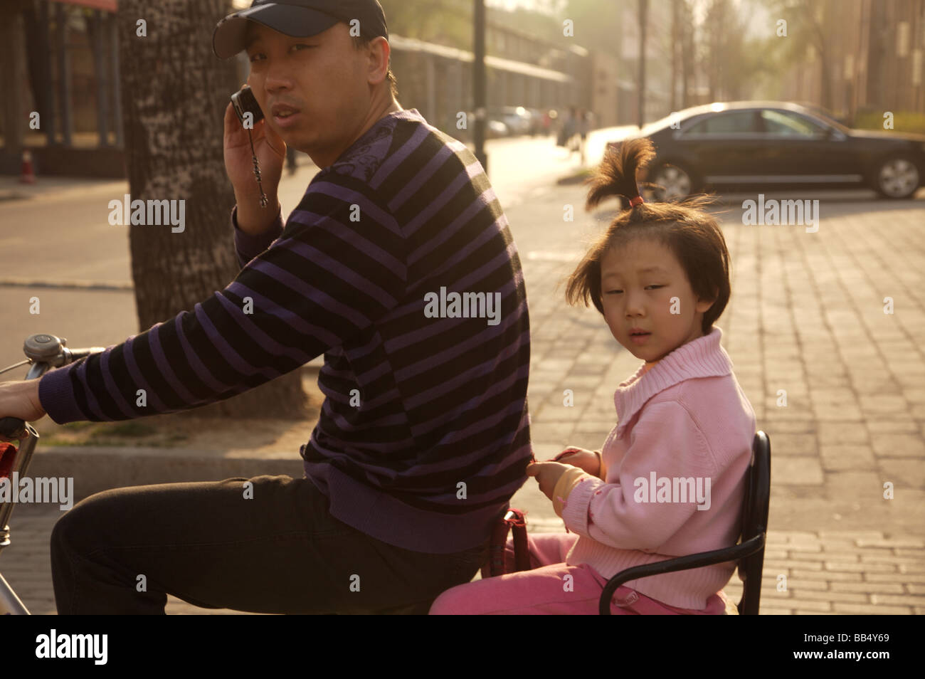 A man on the phone cycles with his daughter Stock Photo - Alamy