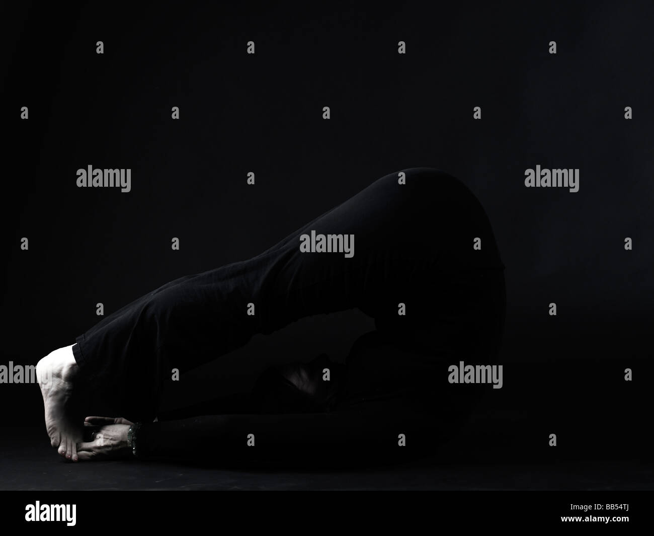 Halasana (Plow Pose) yoga inversion hands holding toes Stock Photo - Alamy