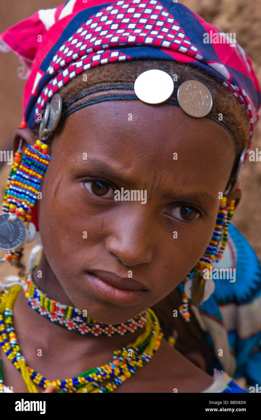 A girl in southwestern Niger wears the traditional bead and silver coin ...