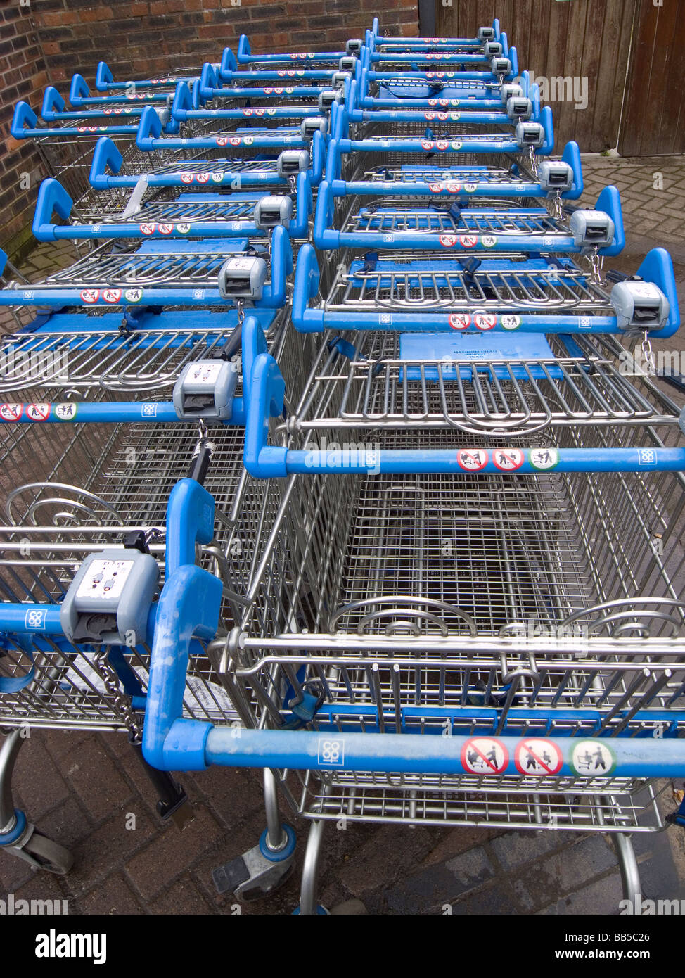 A stack of Co-op supermarket pay to use trolleys with blue handles ...