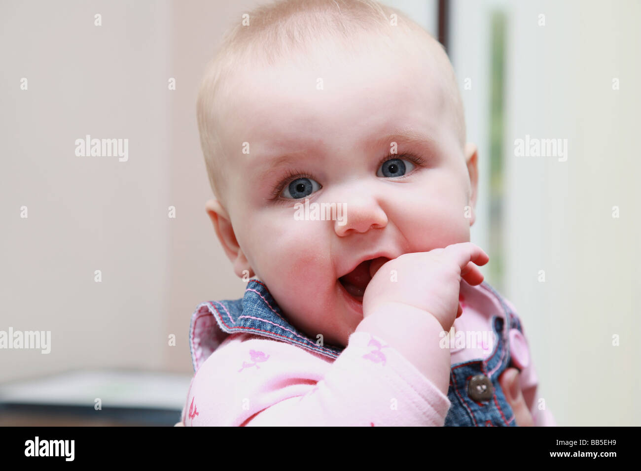 Baby girl chewing her hand Stock Photo - Alamy