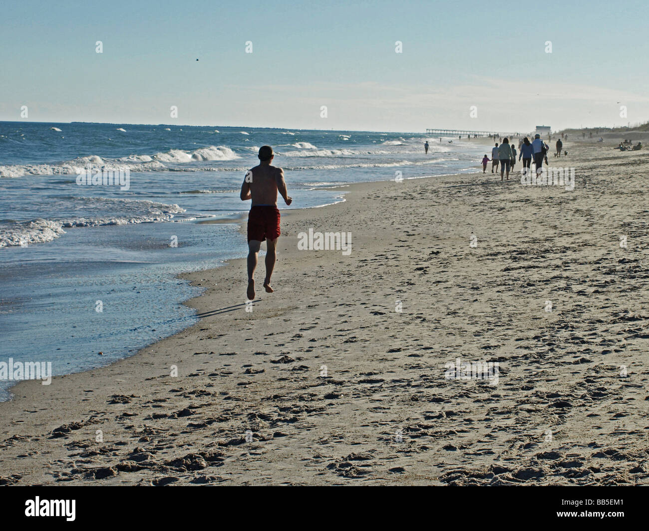 solo beach runner gaining on a crowd in the distance, waves and sand ...