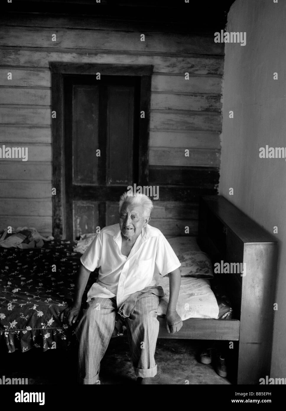 Frail Belizean man sitting on bed, Corozal, Belize, Central America ...