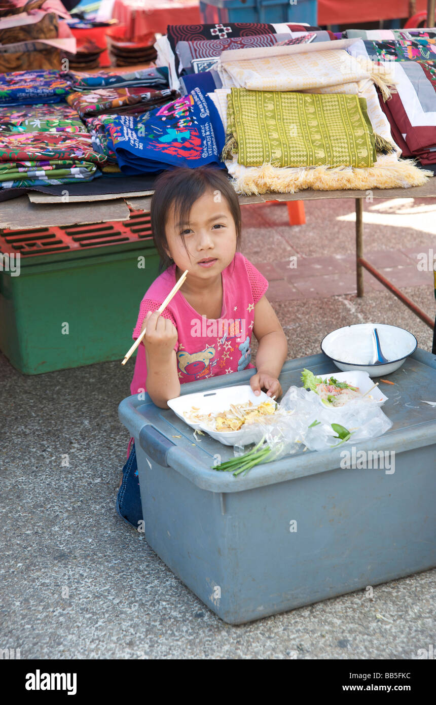 A Chiang Mai market stall child eats lunch on her stall in Chiang Mai ...