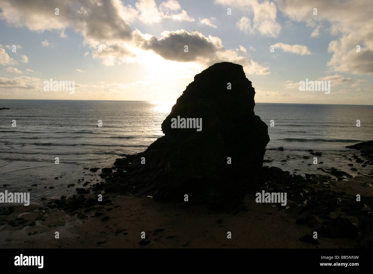 Sun going down behind large rock on beach, Newquay, Cornwall Stock ...