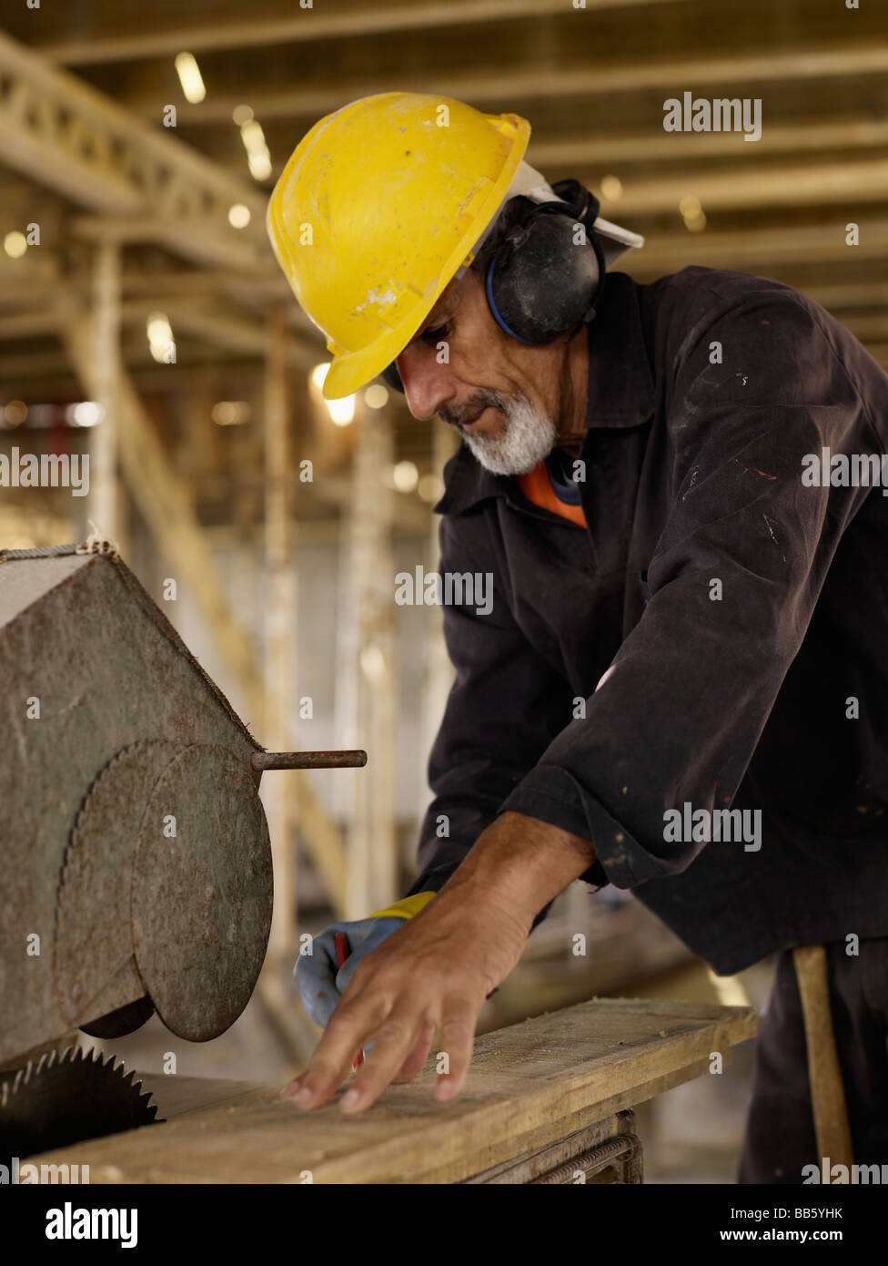 Hispanic worker using saw at construction site Stock Photo - Alamy