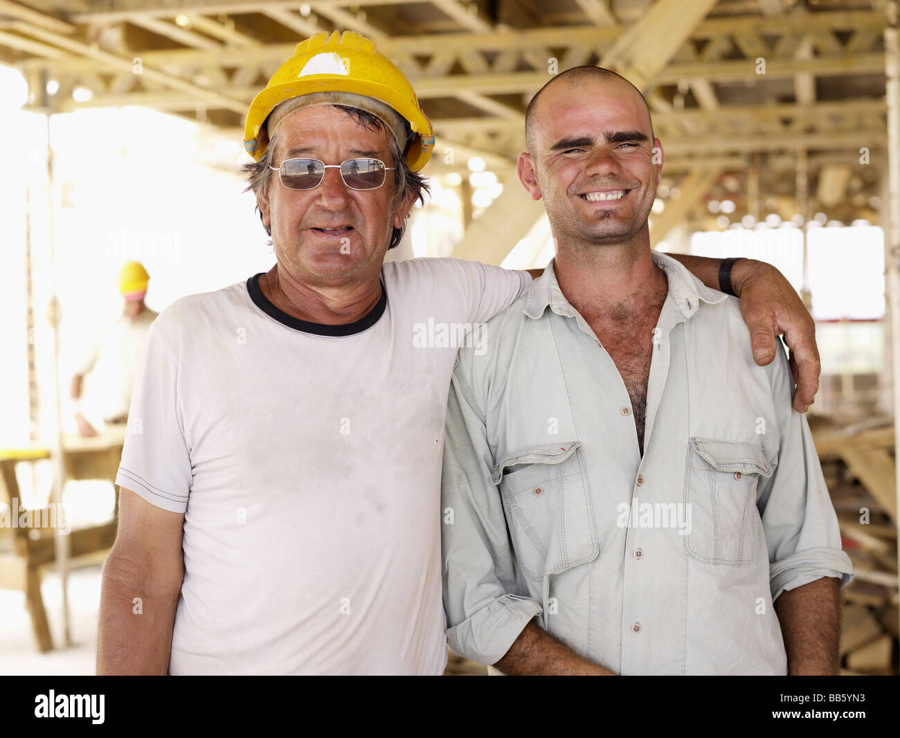 Hispanic workers hugging construction site Stock Photo - Alamy