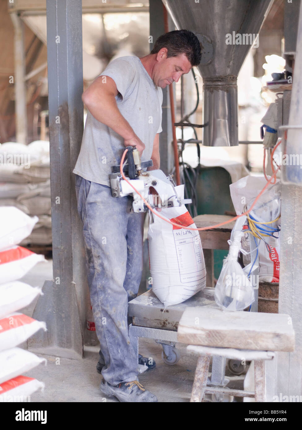 Hispanic worker sealing bag in factory warehouse Stock Photo - Alamy