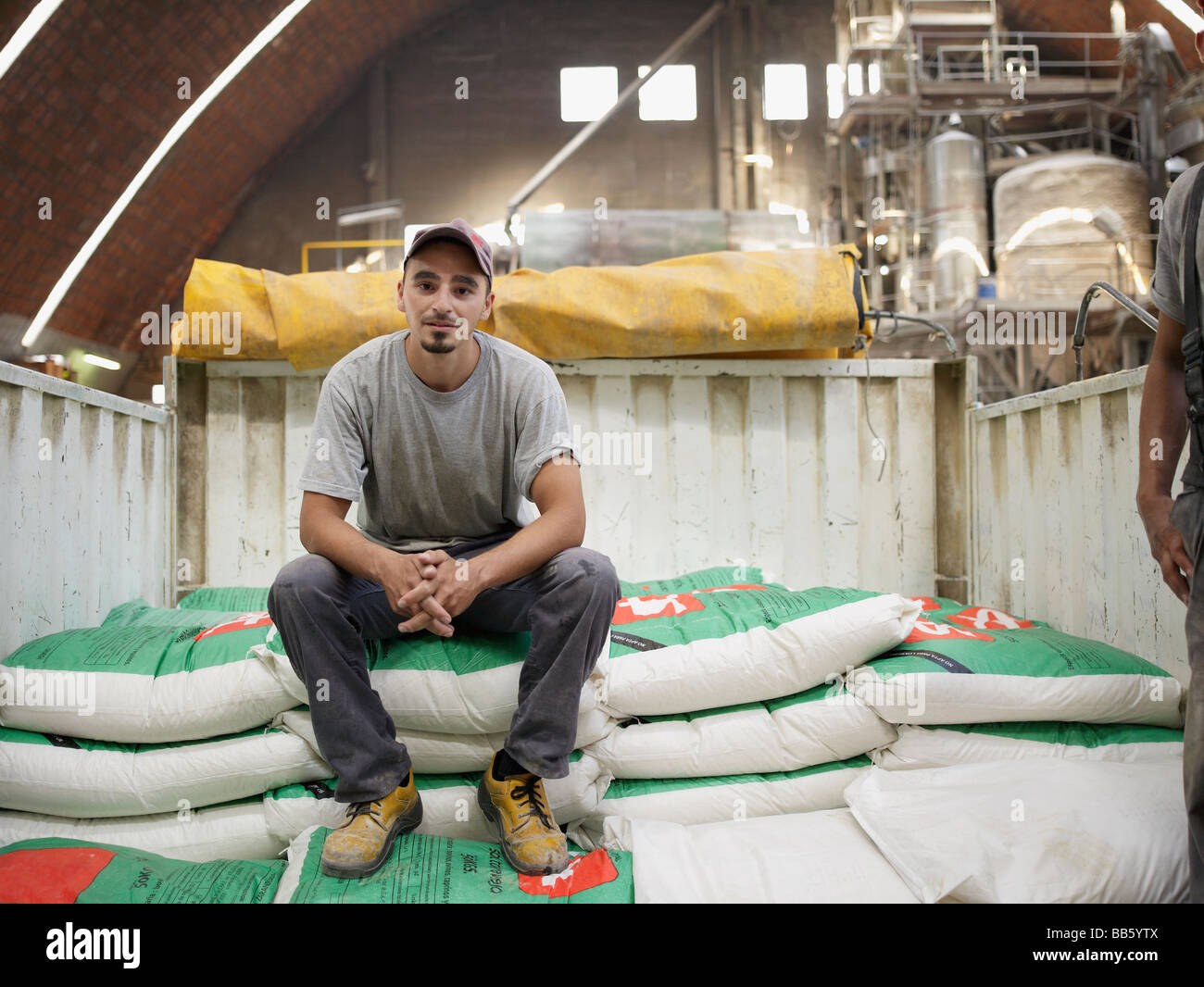 Hispanic worker sitting on bag in factory Stock Photo - Alamy