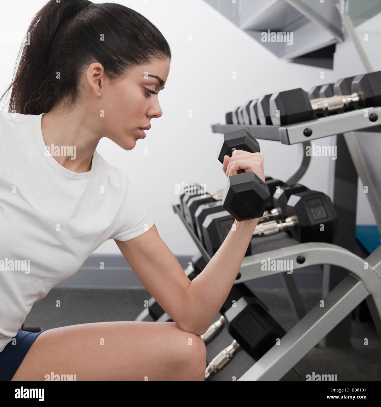 Hispanic woman using hand weights in health club Stock Photo - Alamy