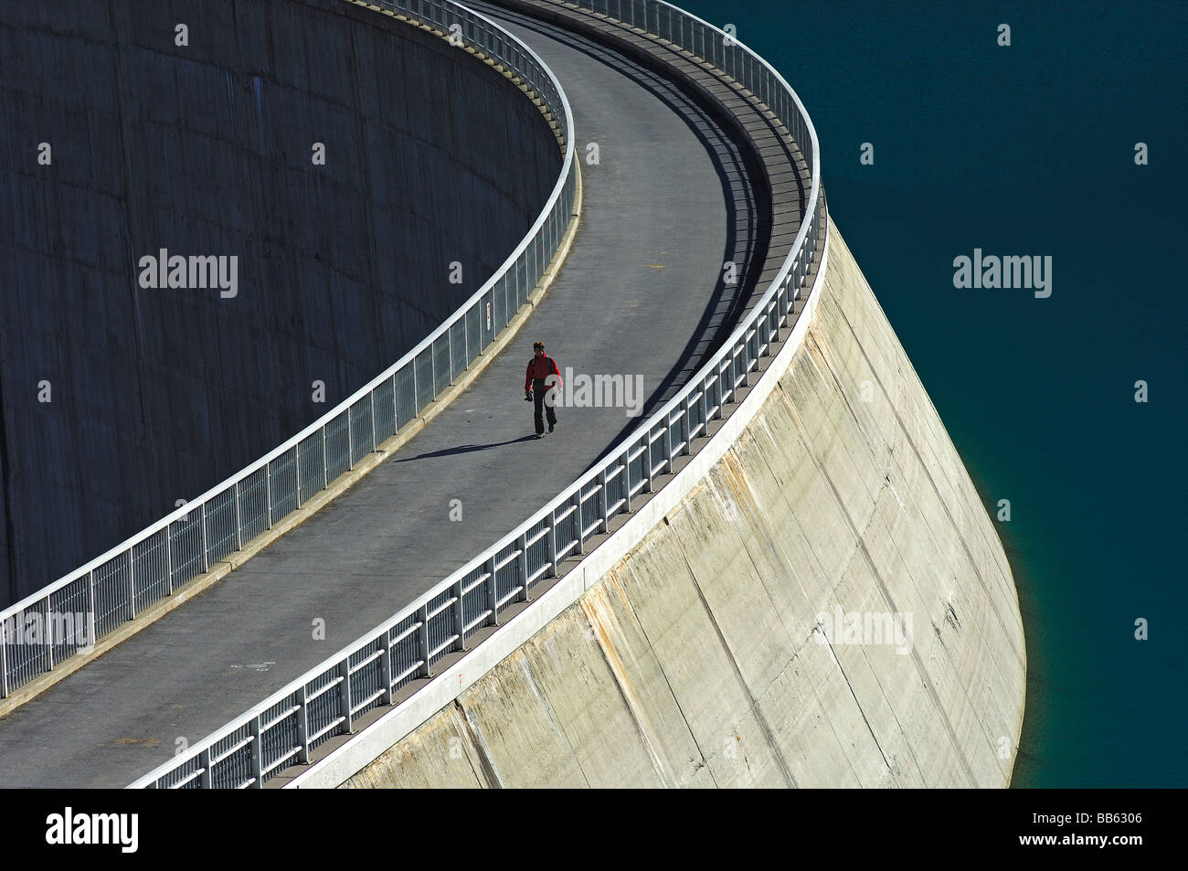 Pedestrian on the dam crest of the concrete gravity arch dam Moiry ...