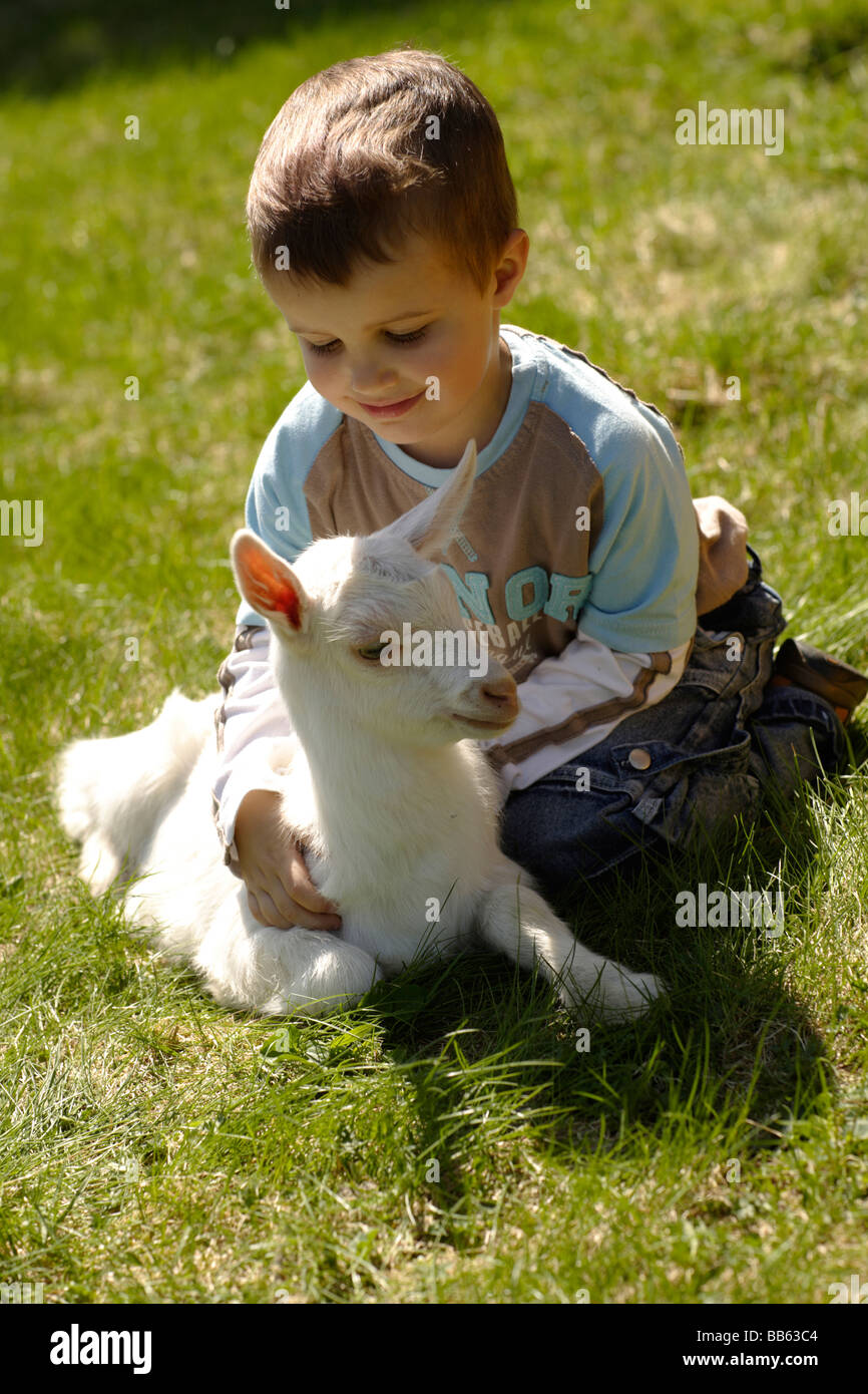 Boy hugging goat in grass Stock Photo - Alamy