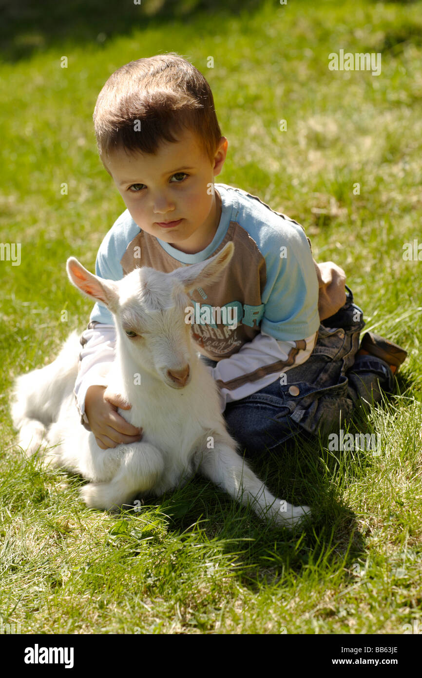 Boy hugging goat in grass Stock Photo - Alamy