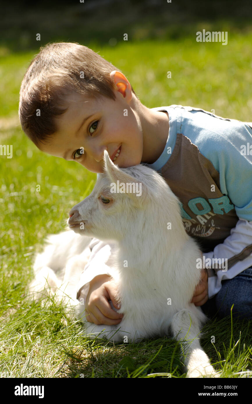 Boy hugging goat in grass Stock Photo - Alamy