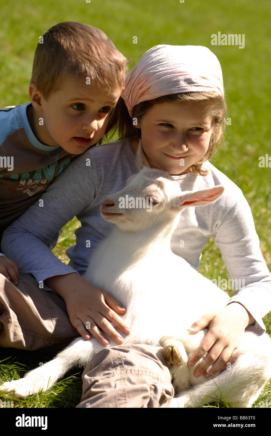 Boy and girl hugging goat in grass Stock Photo - Alamy