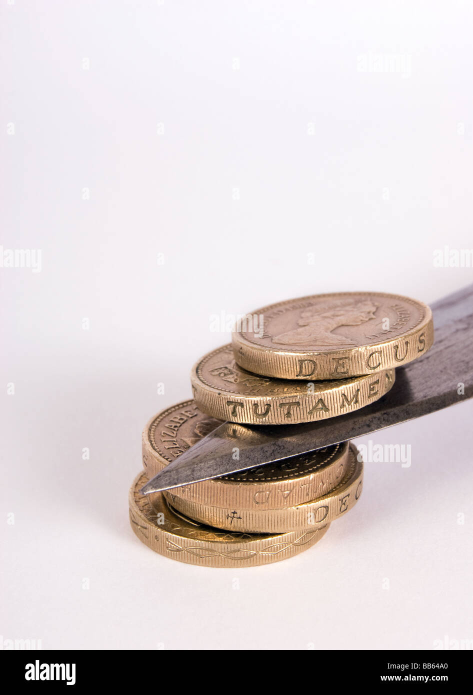Knife cutting through a stack of one pound coins Stock Photo - Alamy