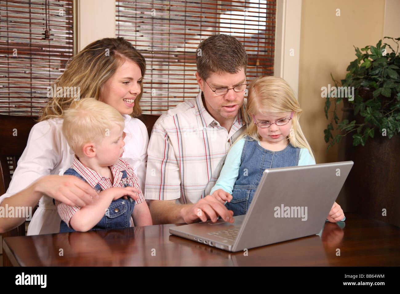 Family of four looking at computer together Stock Photo - Alamy
