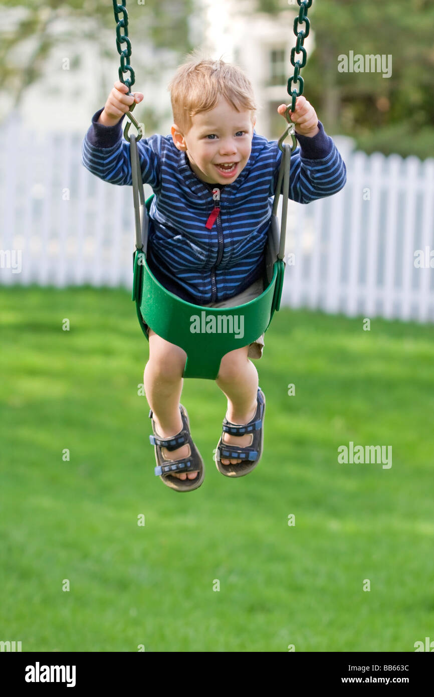 Happy boy playing on outdoor swing Stock Photo - Alamy