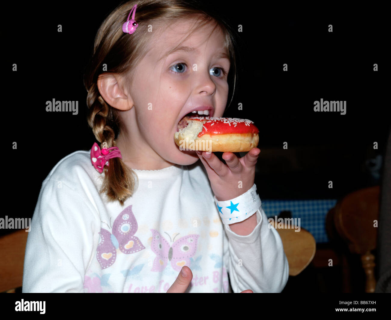 Four Year Old Girl Eating a Doughnut Ring with Pink Icing Stock Photo ...
