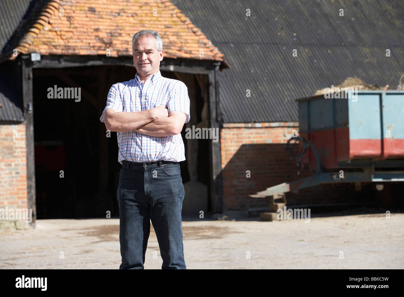 Farmer Standing In Front Of Farm Buildings Stock Photo - Alamy