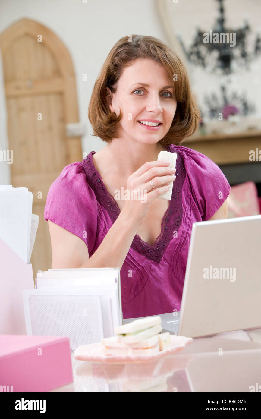 Woman eating lunch at her desk Stock Photo - Alamy