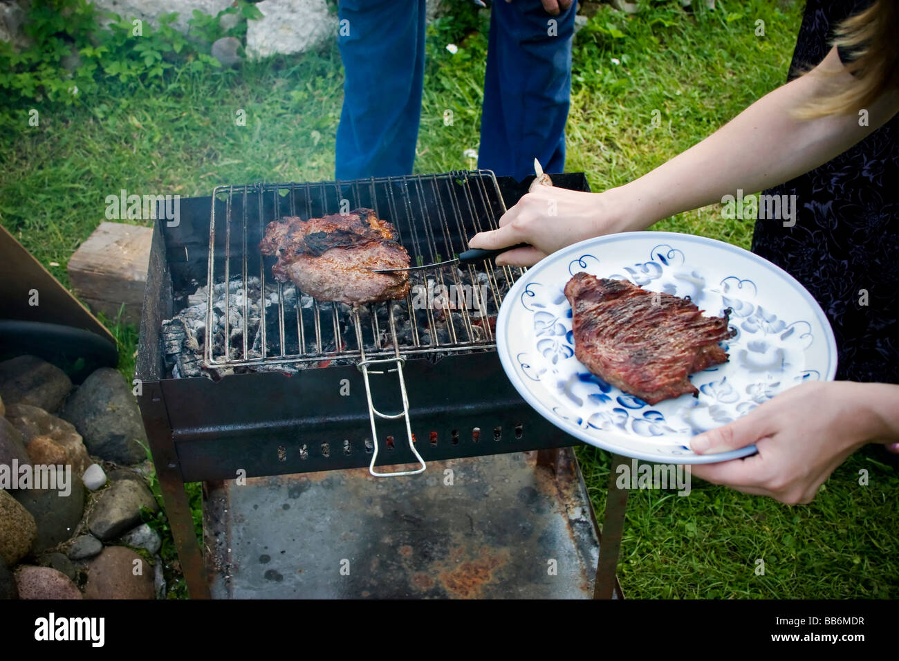 Cooking steak on the grill outdoors "Russian food." A woman is testing ...