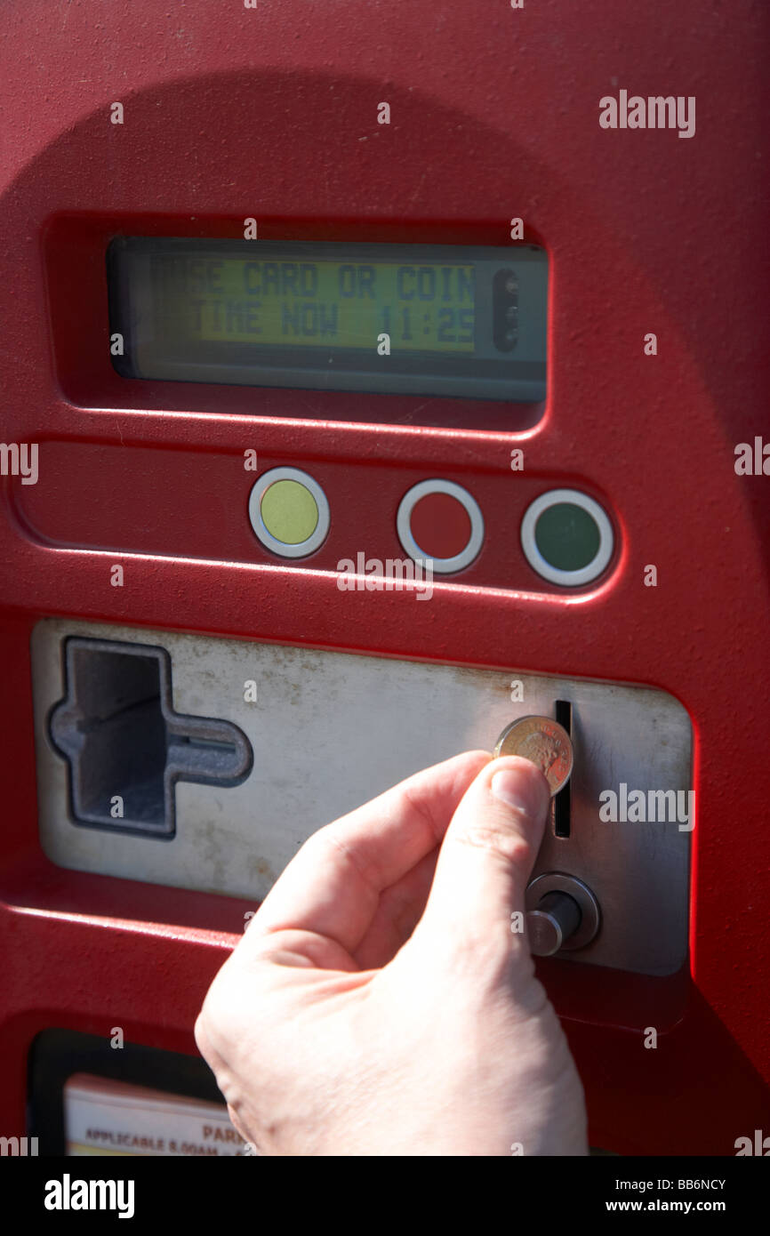 man putting pound coin into pay and display parking machine in the uk ...