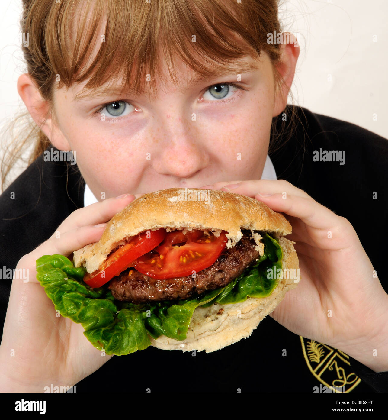 Schoolgirl eating a beefburger with a healthy salad filling Stock Photo ...
